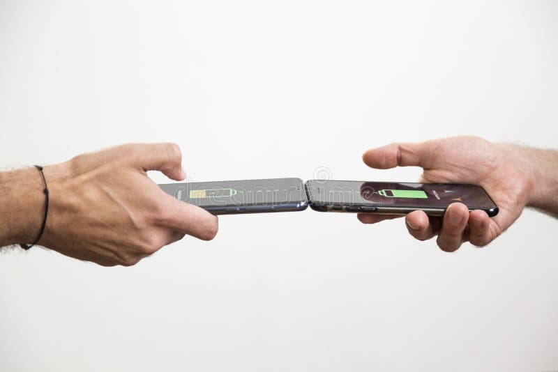 Two Hands Holding Black Smart Phones while they are Wireless Charging ...