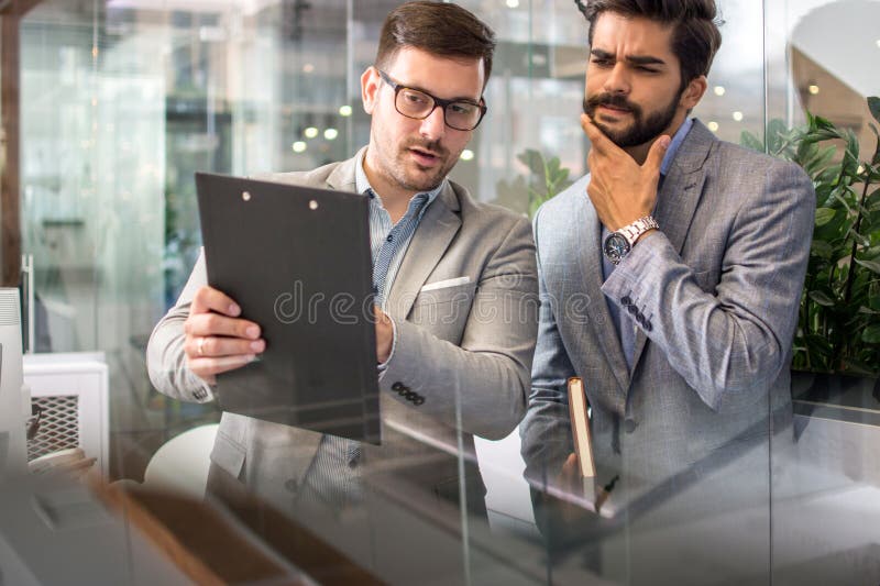 Two Handsome Businessmen Discussing Contract in Modern Office Stock ...