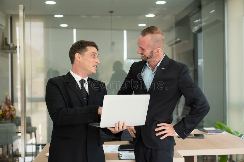 Two Handsome Young Businessmen in Suits Holding Laptops Discussing Work ...