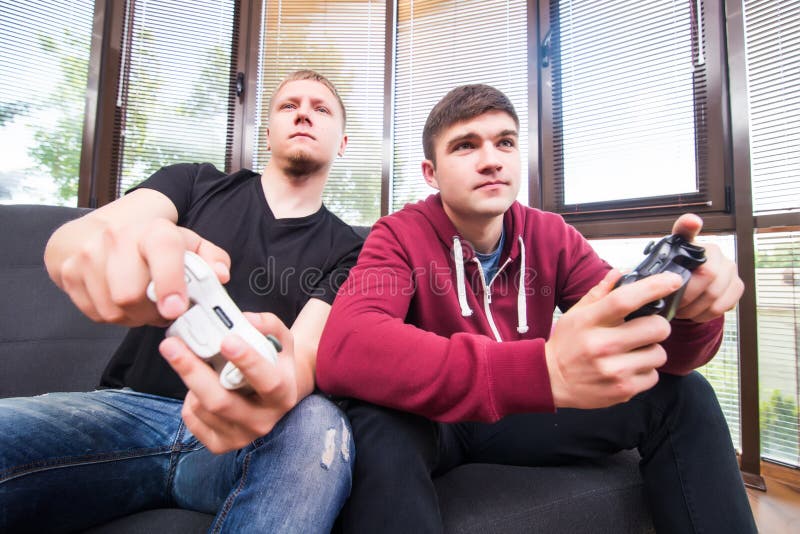 Two Handsome Young Men Playing Video Games while Sitting on Sofa Stock ...
