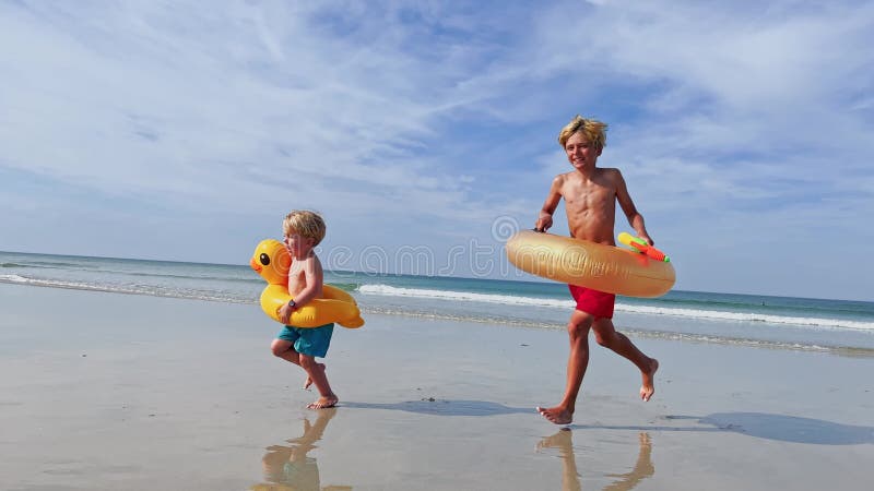 Two Happy Boys Run with Inflatable Buoys Doughnut and Duck Stock ... Two Happy Boys Run with Inflatable Buoys Doughnut and Duck Stock ...