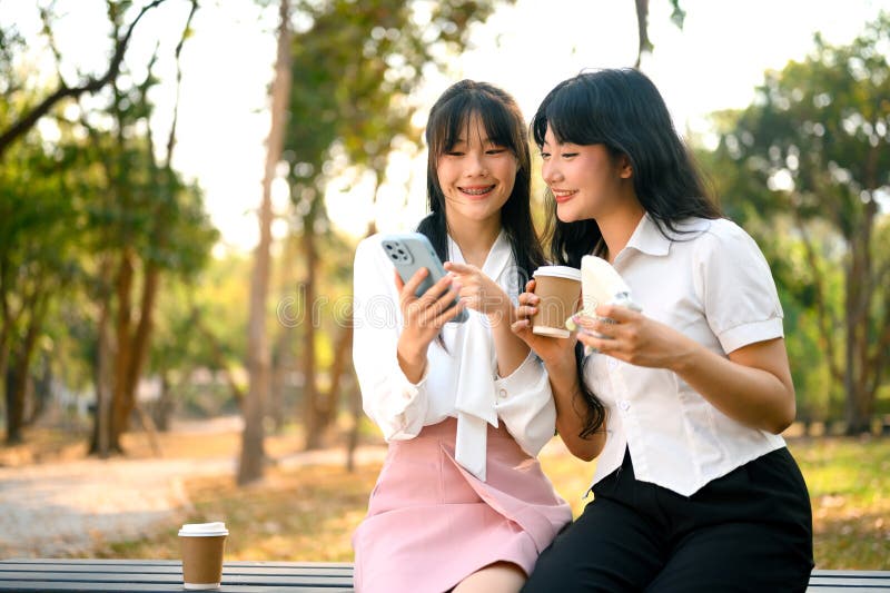 Two Happy Female Friends Talking and Using Mobile Phone Together in the ...