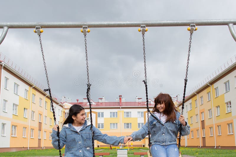 Two Happy Girls are Swinging on a Swing, Laughing Stock Photo - Image ...