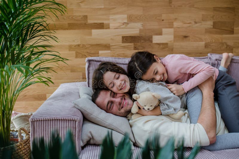 Two Happy Sisters Having Fun with Father, Lying on Sofa at Home. Stock ...