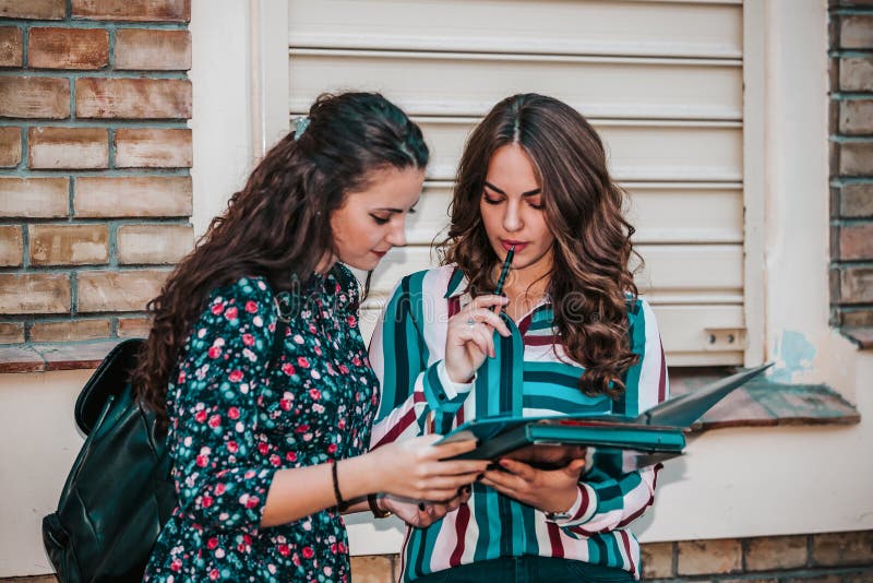 Two Happy Students Reading a Notebook and Commenting in the Street ...