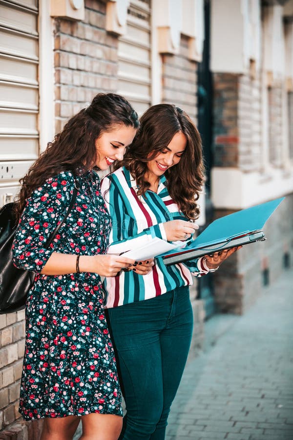 Two Happy Students Reading a Notebook and Commenting in the Street ...