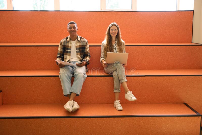 Two Happy Students Sitting and Using Gadgets in University Stock Photo ...