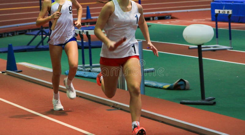 Two High School Runners Running in an Indoor Track Relay Race Stock ...
