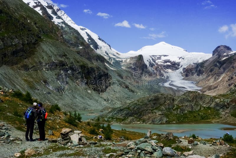 Two Hikers Talking at a Place in the Mountains with Snow and a Glacier ...