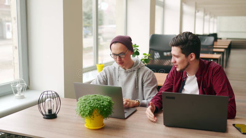 Two Hipster Coworkers Sharing Ideas about Project Sitting with Laptops ...
