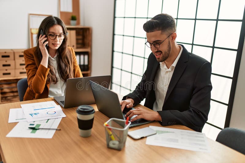 Two Hispanic Business Workers Working Using Smartphone and Laptop at ...