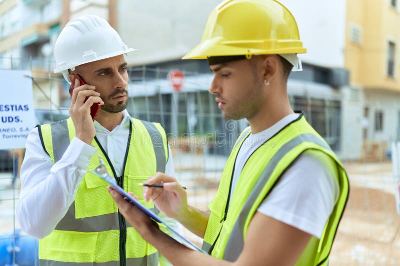 Two Hispanic Men Architects Writing on Document Talking on Smartphone ...