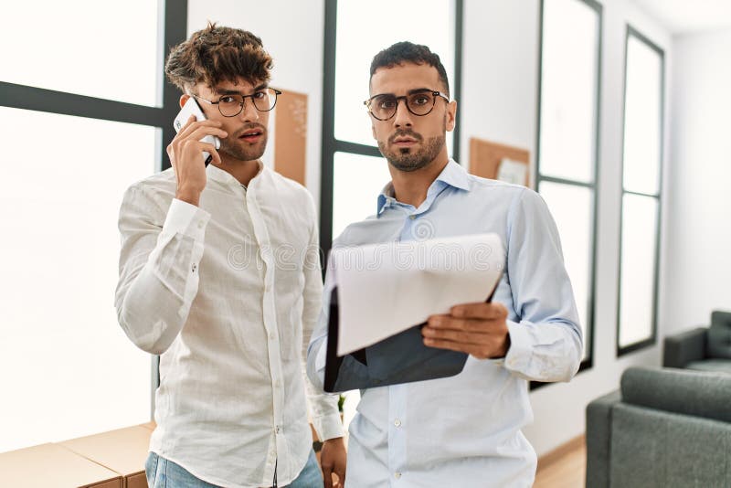 Two Hispanic Men Business Workers Reading Document and Talking on the ...