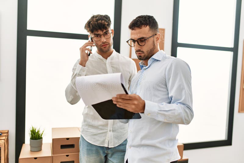 Two Hispanic Men Business Workers Reading Document and Talking on the ...