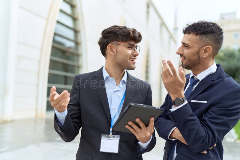 Two Hispanic Men Business Workers Using Touchpad Speaking at Street ...