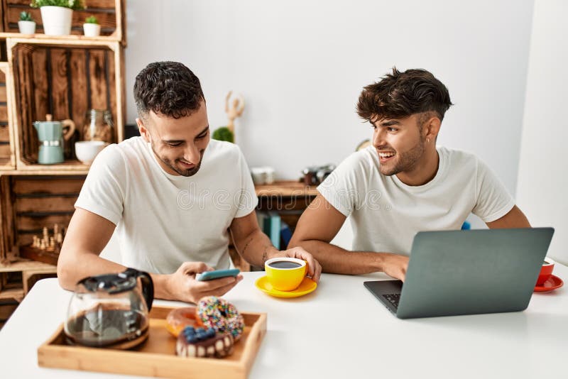 Two Hispanic Men Couple Having Breakfast Using Smartphone and Laptop at ...