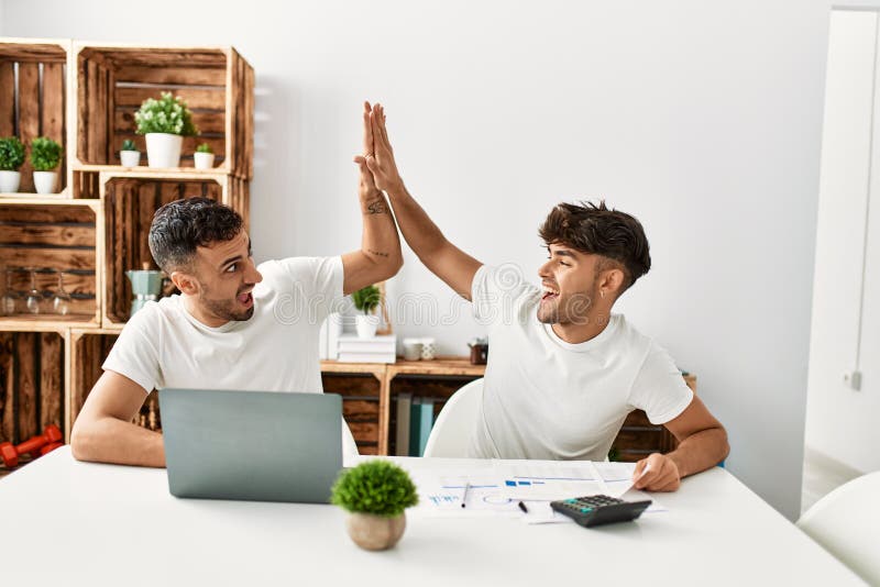 Two Hispanic Men Couple High Five Hands Raised Up Using Laptop Working ...