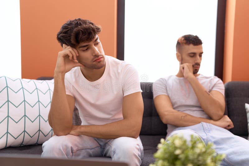 Two Hispanic Men Couple Sitting on Sofa with Sad Expression at Home ...