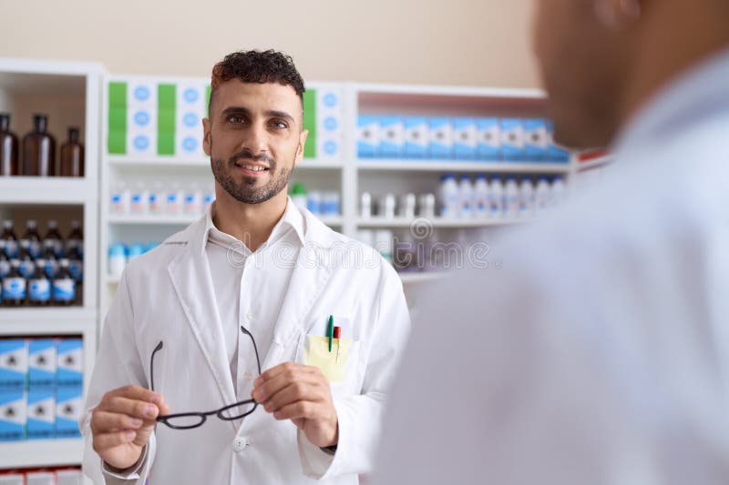 Two Hispanic Men Pharmacist Speaking To Client Holding Glasses at ...