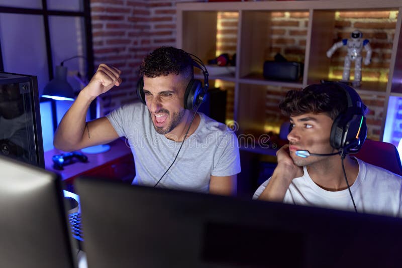 Two Hispanic Men Streamers Playing Video Game with Winner Expression at ...