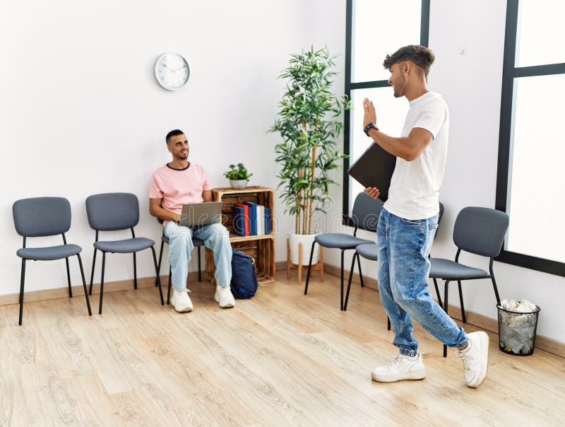 Two Hispanic Men Using Laptop Saying Bye at Waiting Room Stock Photo ...