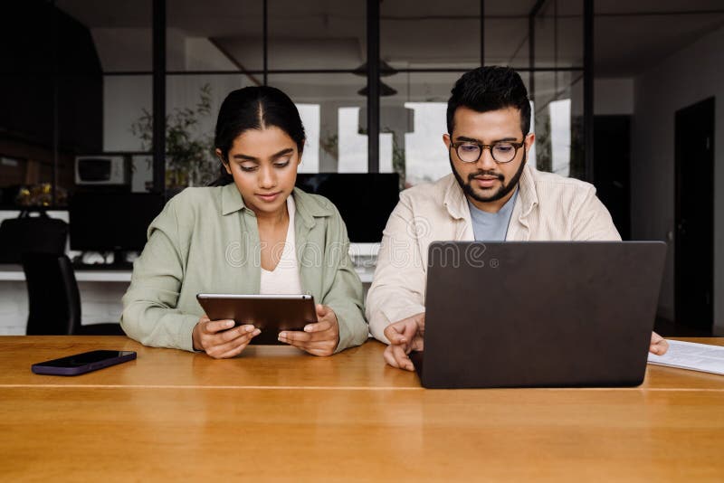 Two Indian Colleagues Using Laptop and Tablet while Working Together in ...