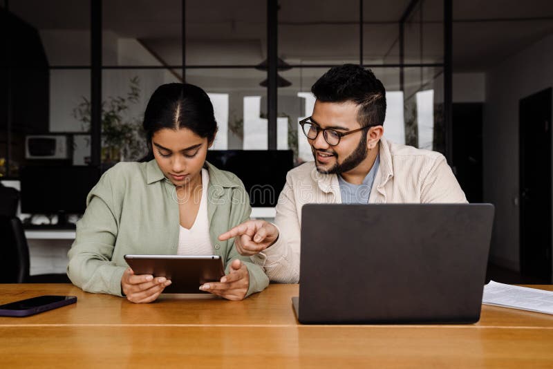 Two Indian Colleagues Using Laptop and Tablet while Working Together in ...