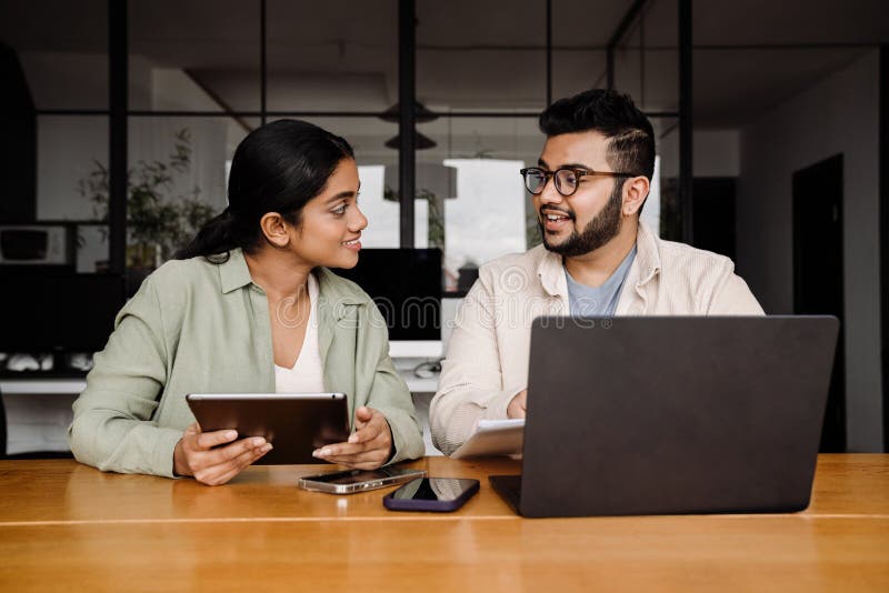 Two Indian Colleagues Using Laptop and Tablet while Working Together in ...