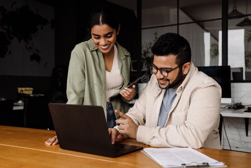 Two Indian Colleagues Using Laptop and Tablet while Working Together in ...