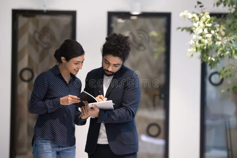 Two Indian Employees Discuss Work Standing in Modern Office Hallway ...