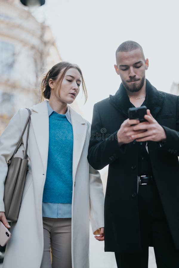 Two Individuals Discussing Together while Using a Smart Phone Outdoors ...