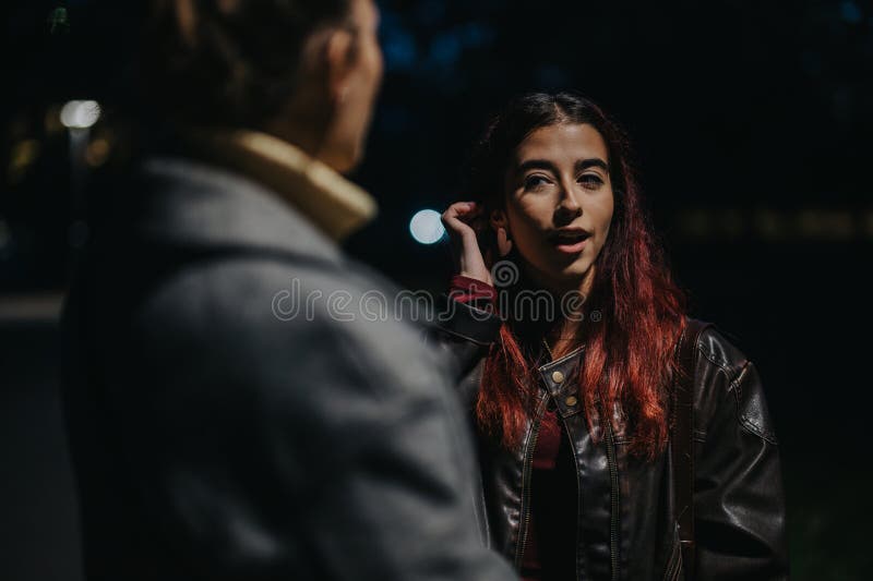 Two Women Interacting Outdoors at Night with Expressive Gestures and ...