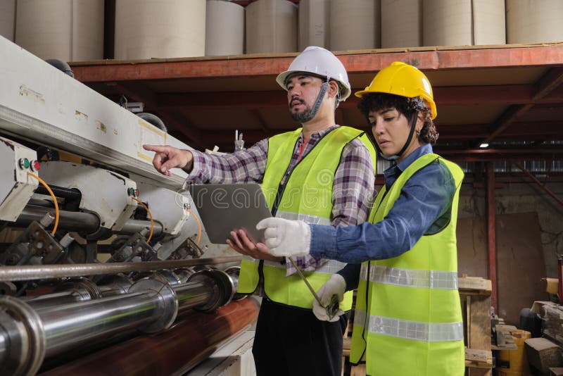 Two Industrial Workers Use a Laptop To Check a Paper Manufacturing ...