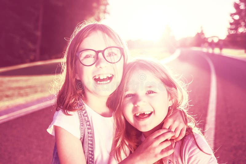 Two Joyful Girls Hugging and Smiling Against the Sunset. Stock Image ... Two Joyful Girls Hugging and Smiling Against the Sunset. Stock Image ...