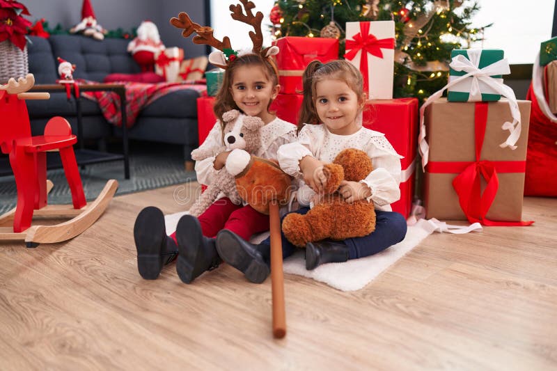 Two Kids Holding Teddy Bear Sitting on Floor by Christmas Tree at Home ...
