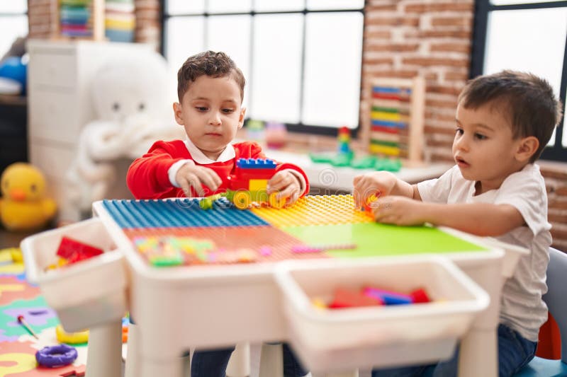 Two Kids Playing with Construction Blocks Sitting on Table at ...