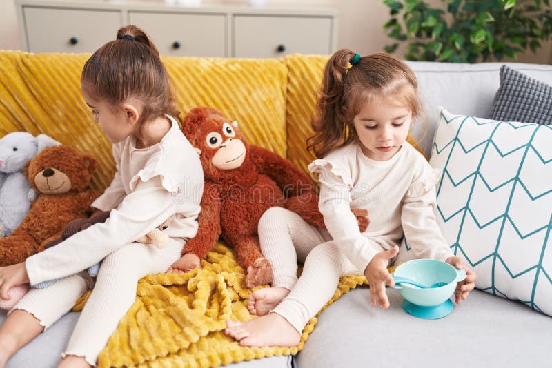 Two Kids Playing with Dolls Sitting on Sofa at Home Stock Photo - Image ...