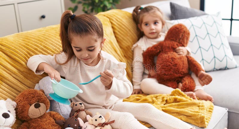Two Kids Playing with Dolls Sitting on Sofa at Home Stock Photo - Image ...