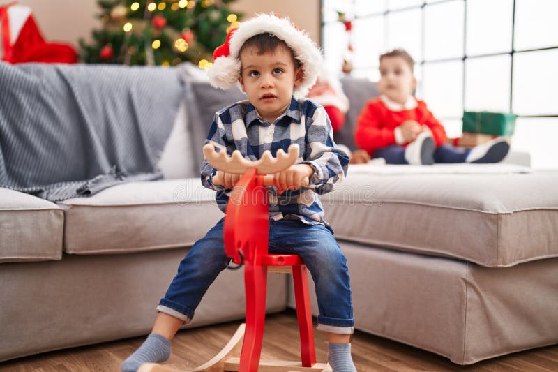 Two Kids Playing with Reindeer Rocking by Christmas Tree at Home Stock ...