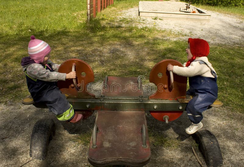 Two Kids Playing on a Teeter Totter Stock Image - Image of cooperates ...