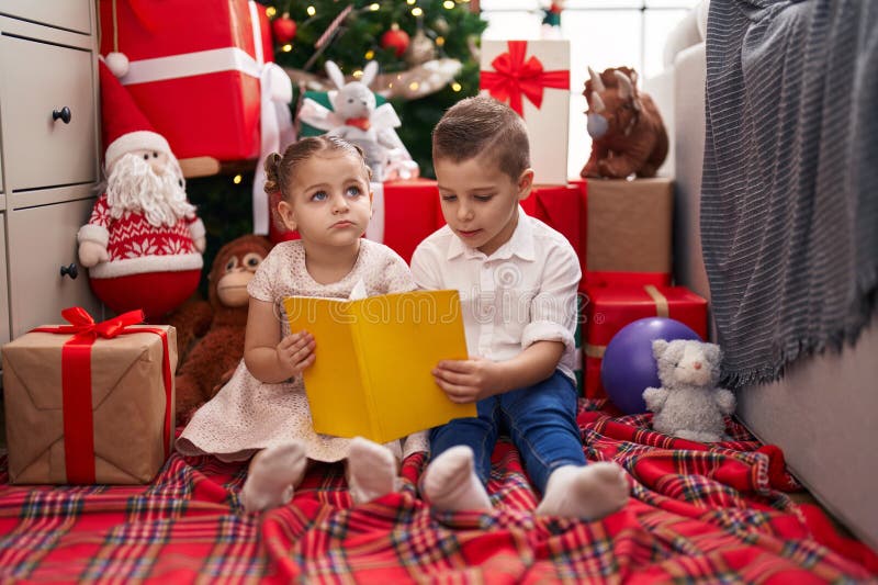 Two Kids Reading Book Sitting on Floor by Christmas Tree at Home Stock ...