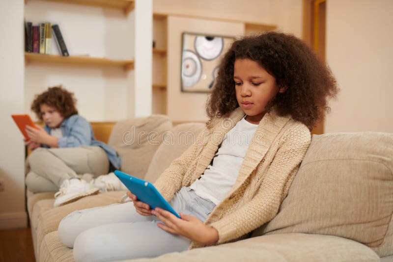 Two Kids Sitting on the Sofa with Devices in Hands Stock Photo - Image ...