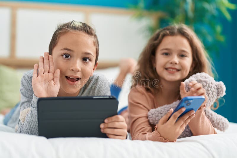 Two Kids Using Smartphone and Touchpad Lying on Bed at Bedroom Stock ...
