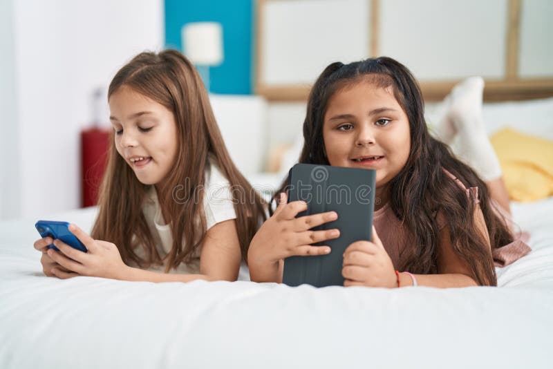 Two Kids Using Smartphone and Touchpad Lying on Bed at Bedroom Stock ...