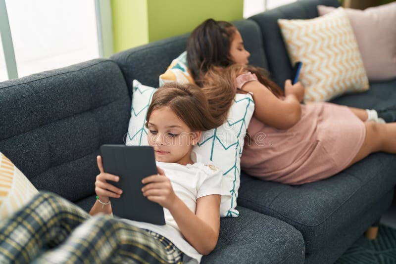 Two Kids Using Smartphone and Touchpad Lying on Sofa at Home Stock ...