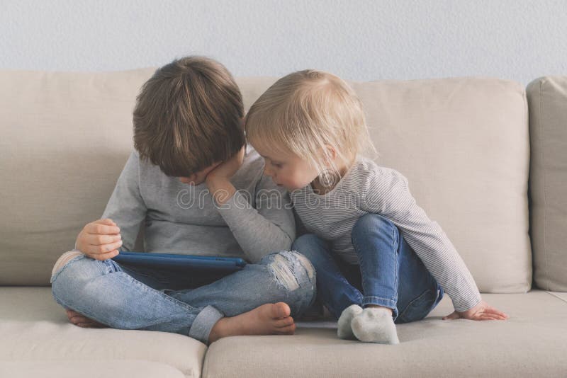 Two Kids Using Tablet on Sofa at Home Stock Photo - Image of preteen ...