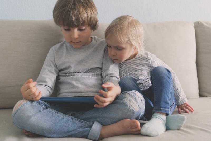 Two Kids Using Tablet on Sofa at Home Stock Image - Image of happy ...