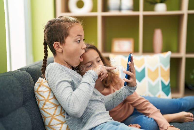 Two Kids Watching Video on Smartphone Sitting on Sofa at Home Stock ...