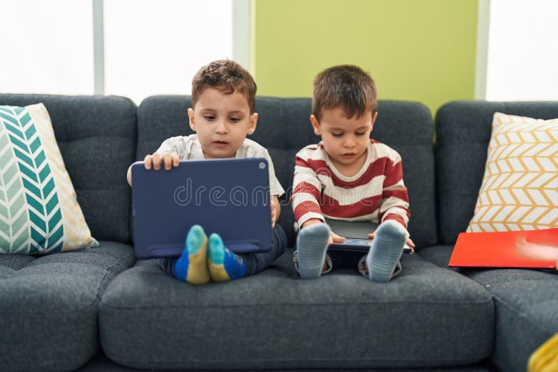 Two Kids Watching Video on Touchpad Sitting on Sofa at Home Stock Photo ...