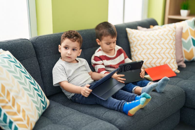 Two Kids Watching Video on Touchpad Sitting on Sofa at Home Stock Photo ...